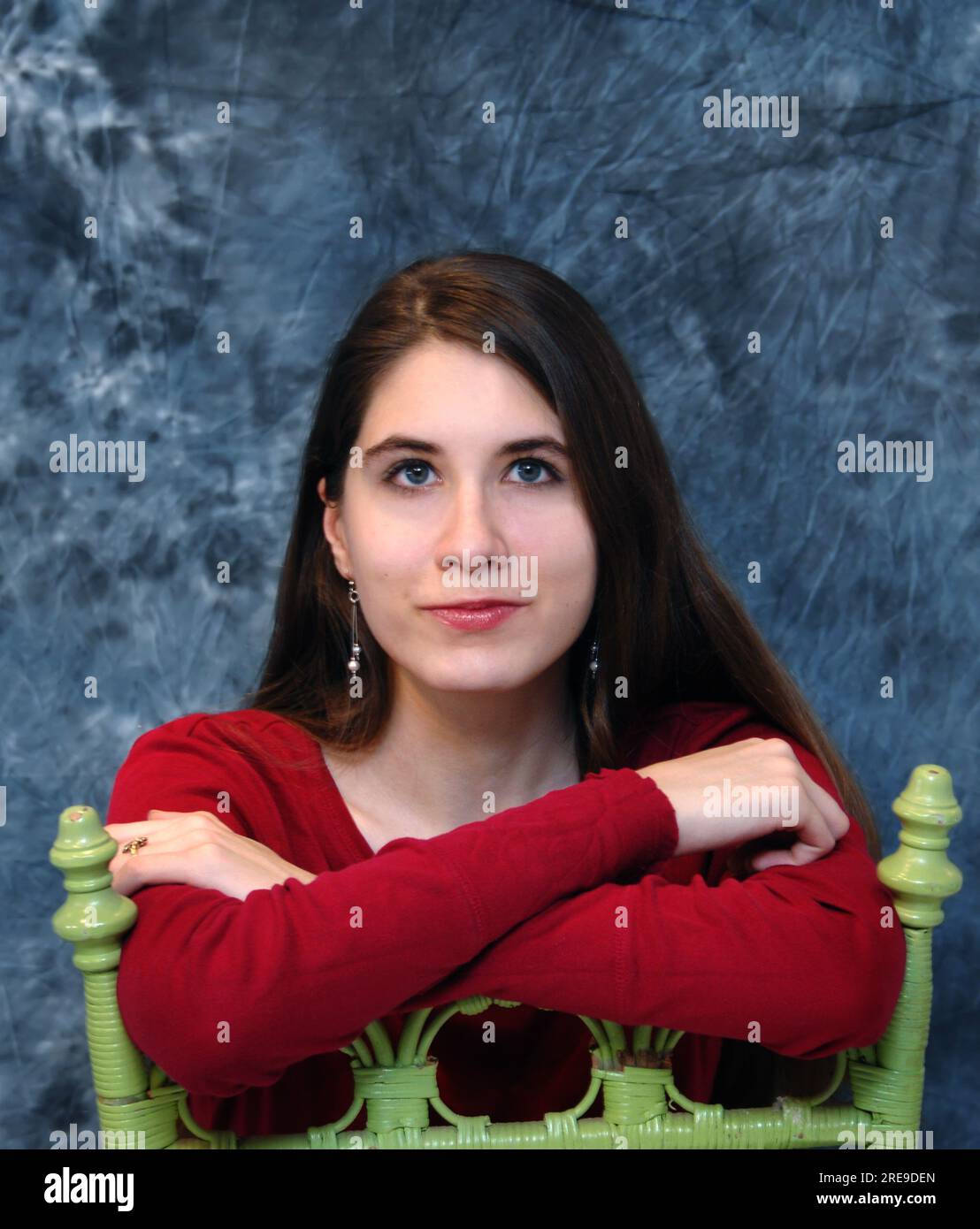 Female teen sits poised in a lime green wooden chair, turned backwards ...