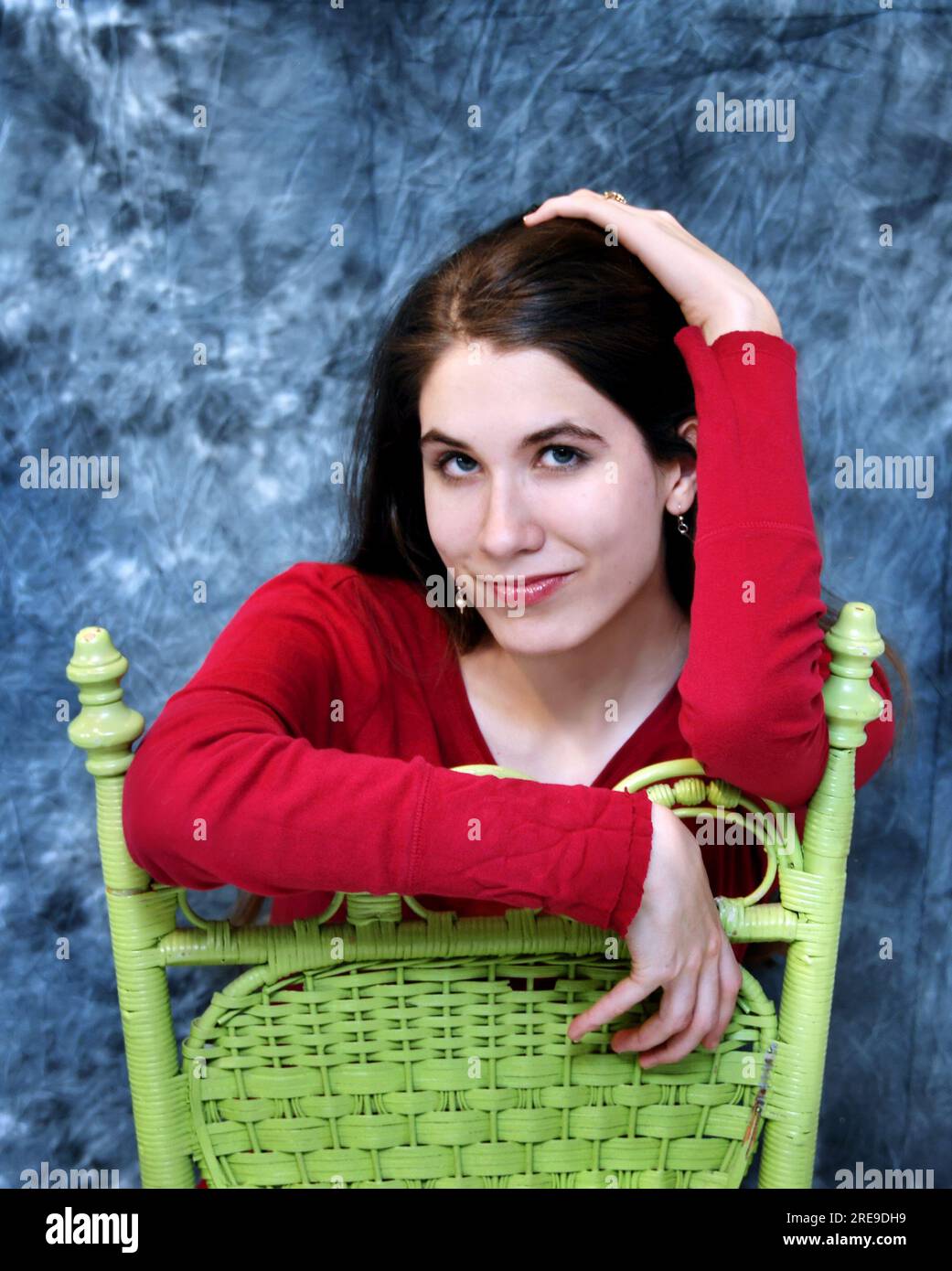 Resting on a chair turned backwards, this female teen smiles with her ...
