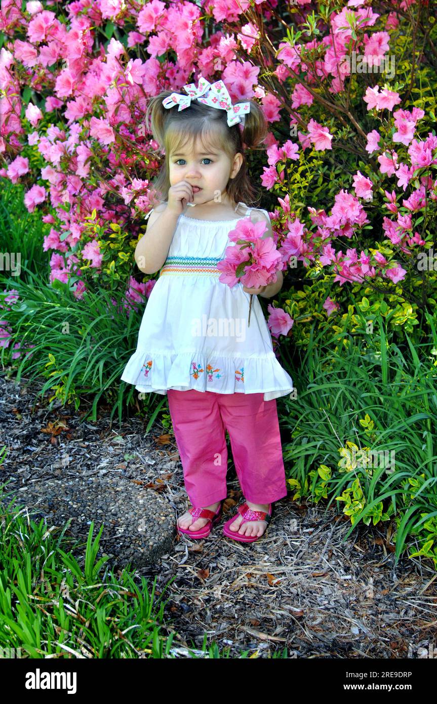 Little girl stands chewing on her thumb and worrying. She is besides an ...