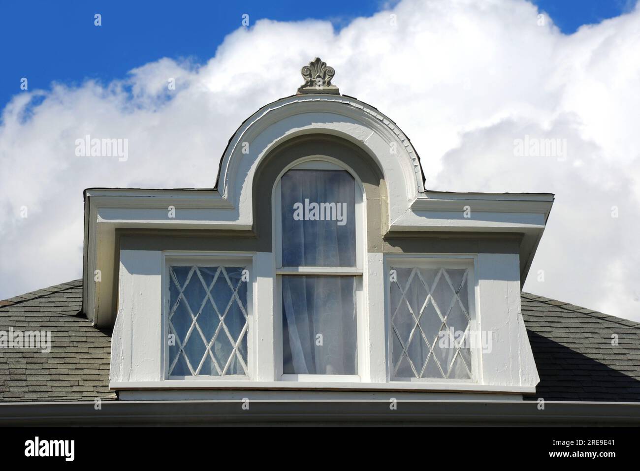 Three glass windows set inside arched dormer on elegant Victorian home ...