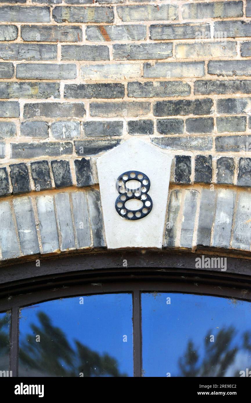 The letter 8 is composed of steel, and mounted on an old brick wall, on ...