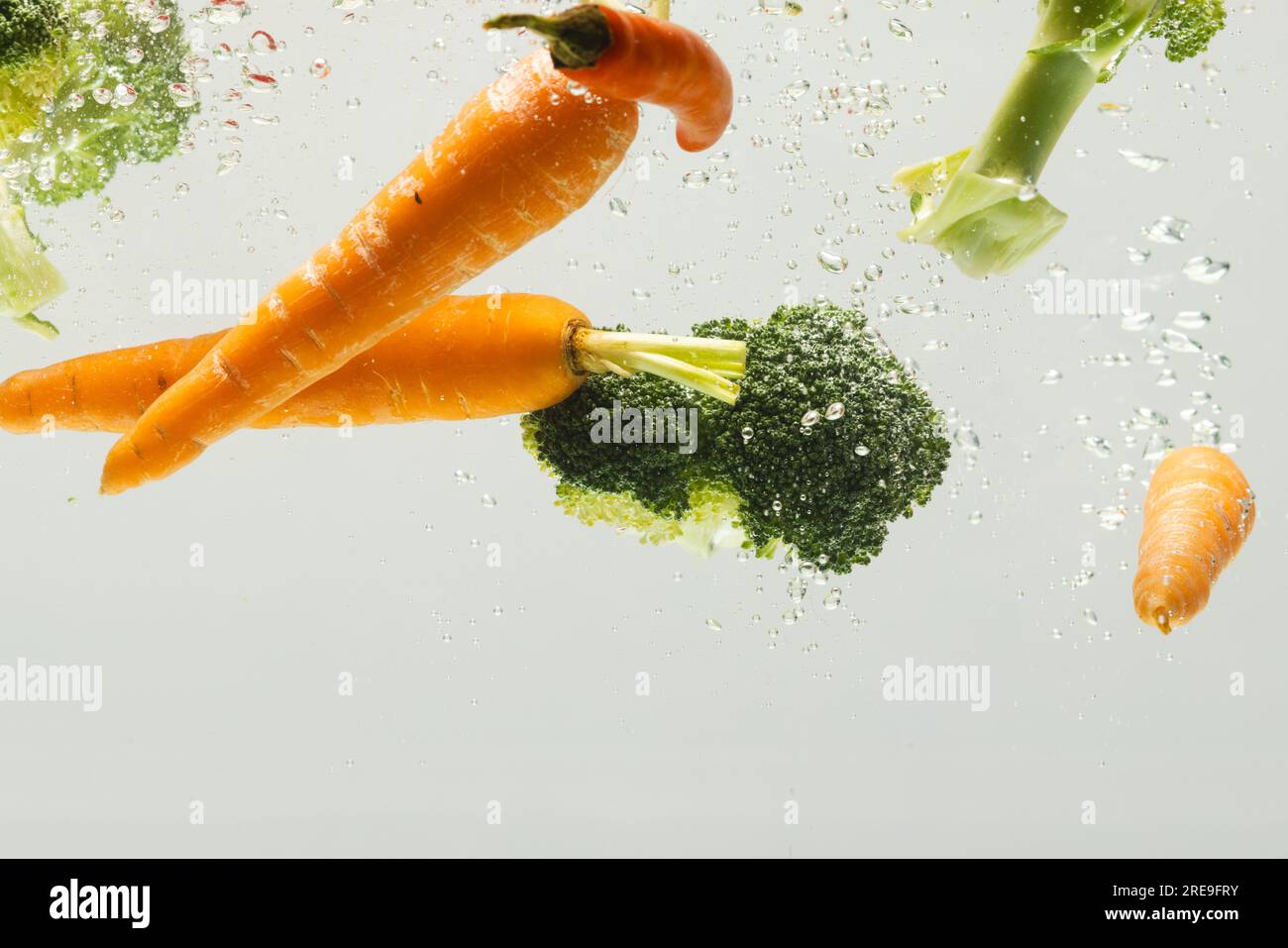 Close up of fresh vegetables falling into water with copy space on ...