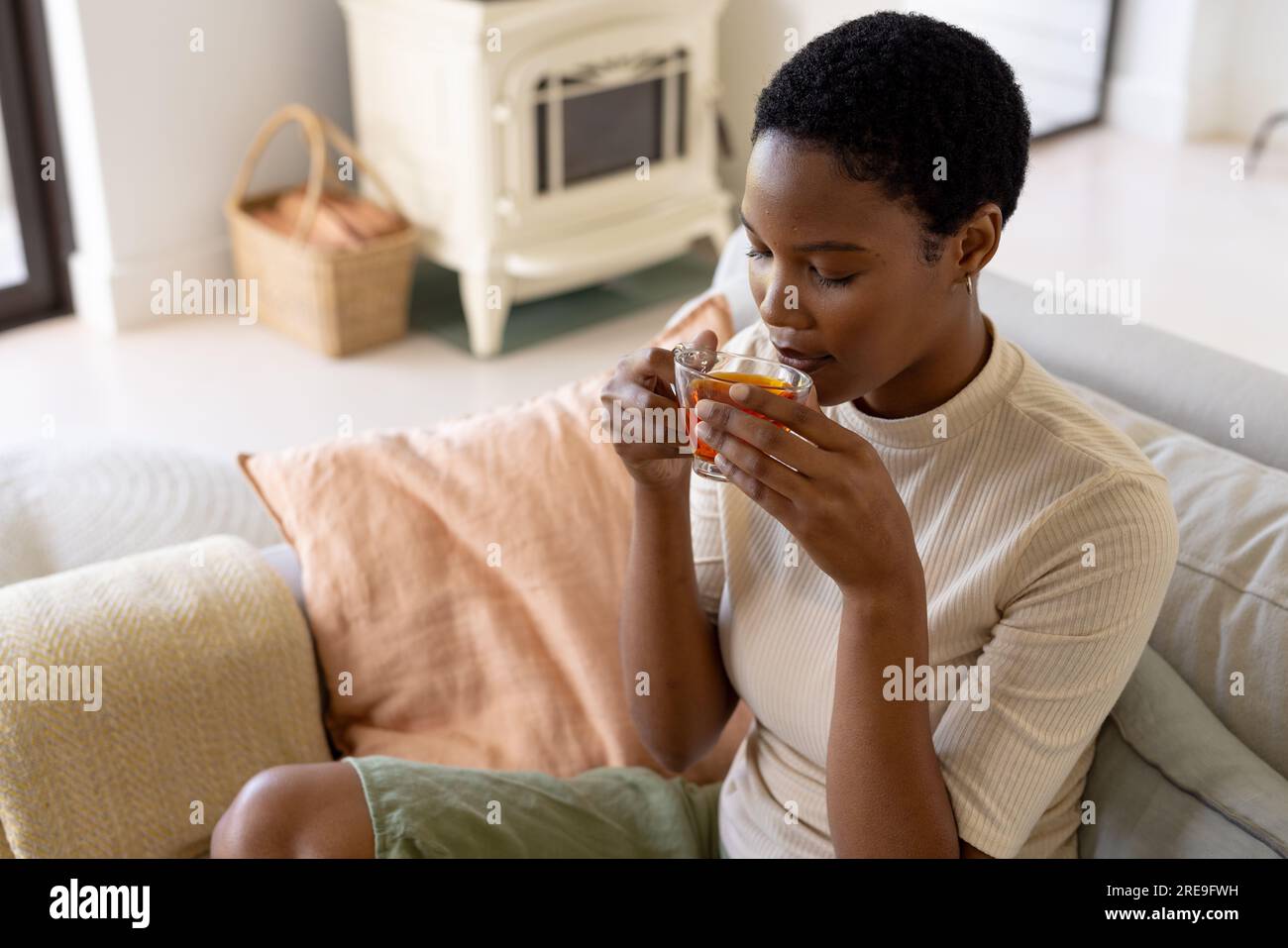 African american woman sitting on sofa and drinking tea Stock Photo - Alamy
