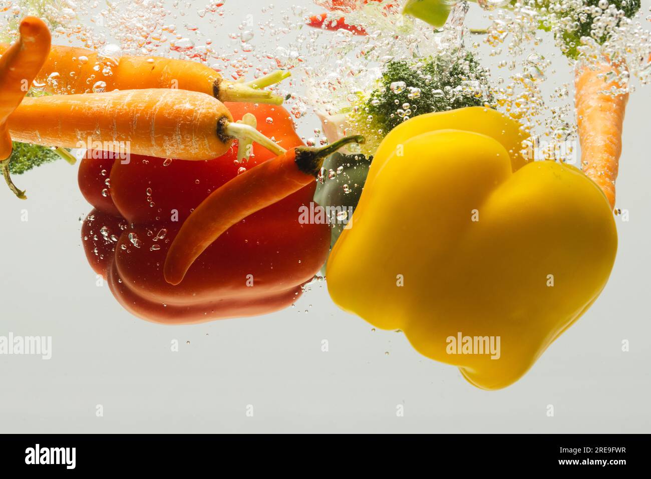 Close up of fresh vegetables falling into water with copy space on ...