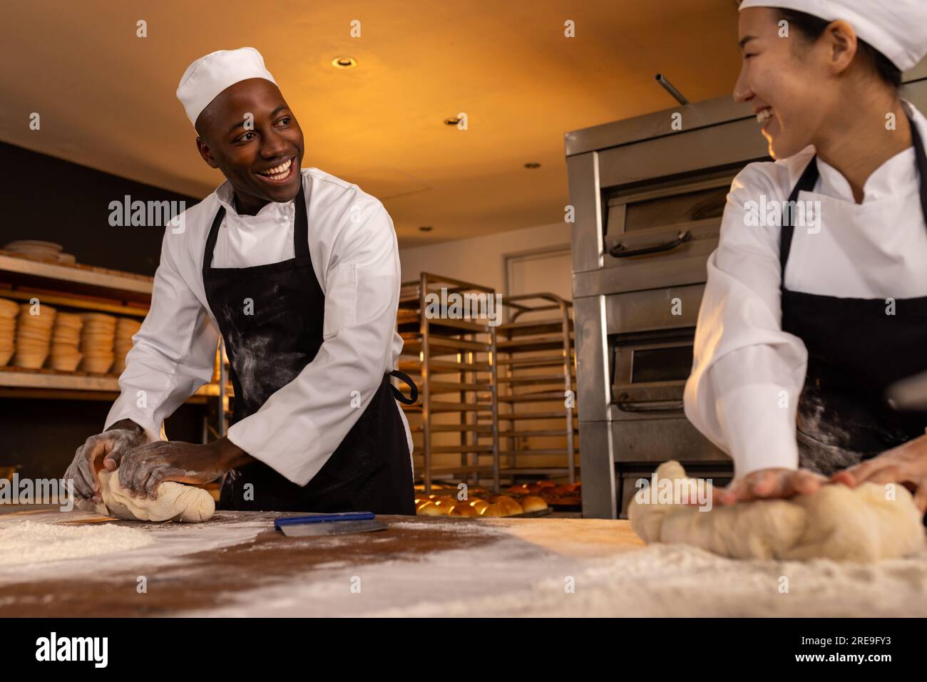 Happy diverse bakers working in bakery kitchen, kneading dough and ...