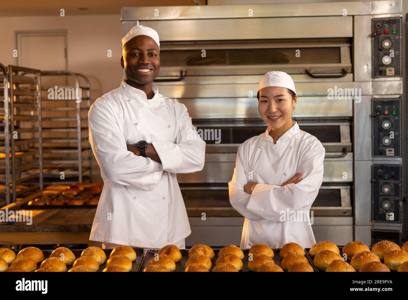 Portrait of happy diverse bakers in bakery kitchen with arms crossed ...