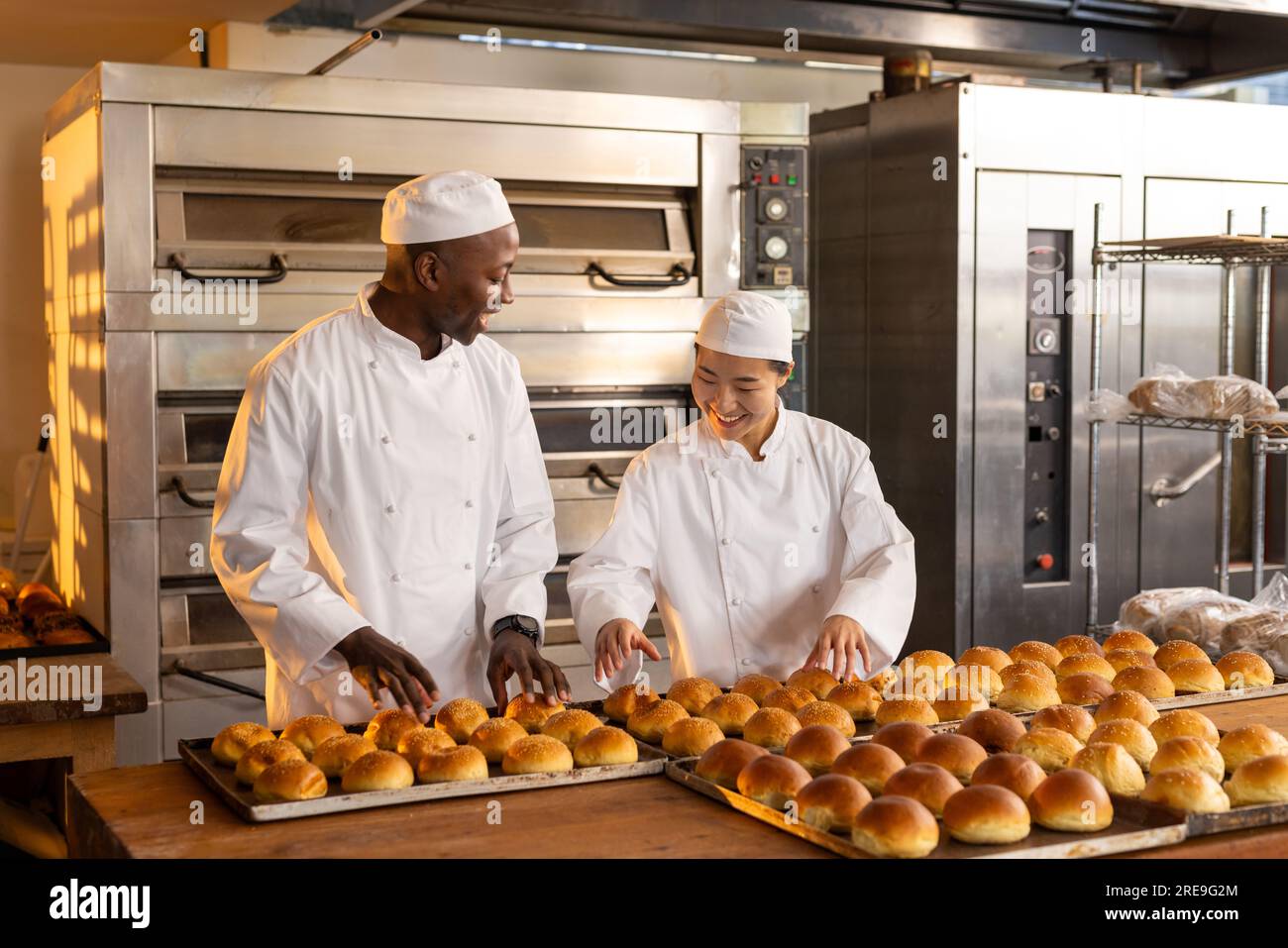 Happy diverse bakers wearing aprons in bakery kitchen and counting ...