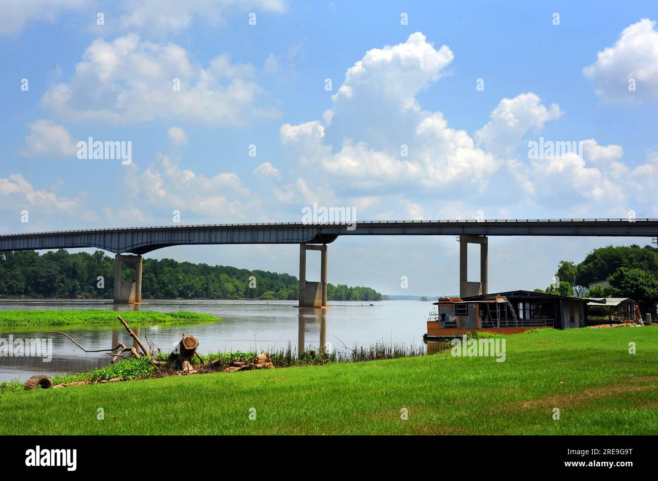 Arkansas River flows placidly beneath bridge overpass. Old houseboat ...