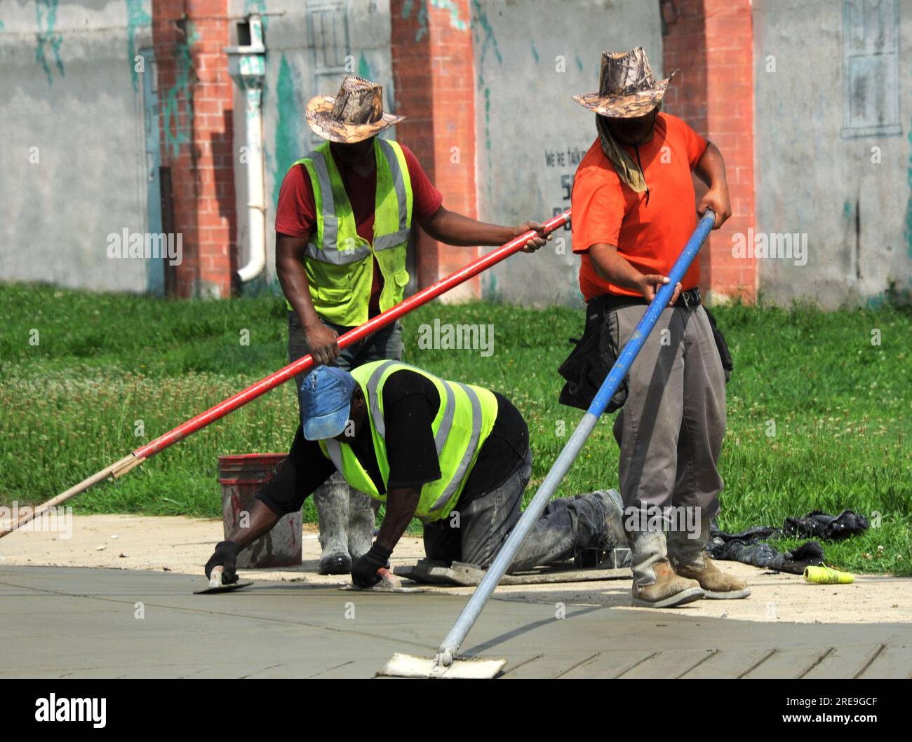 City workers smooth recently poured concrete for sidewalk. One worker ...