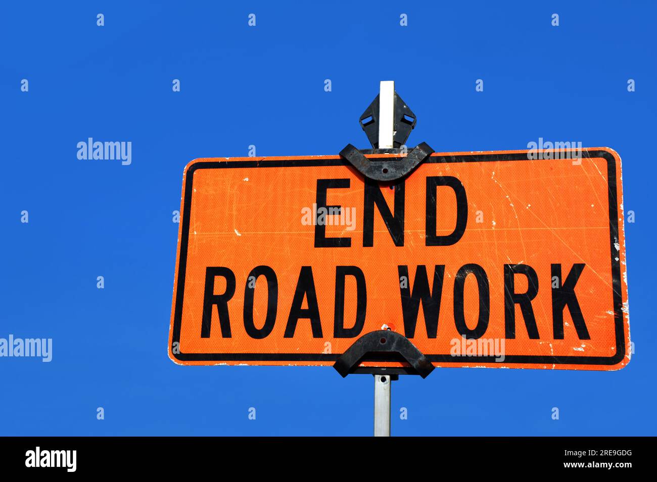 Blue sky frames an end road work sign. Sign is orange with black ...