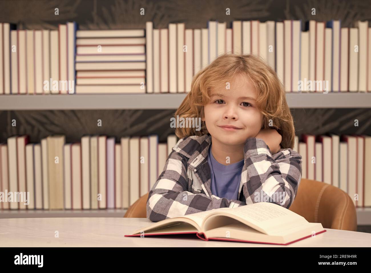 School child studying in school library. Portrait of child reading in ...