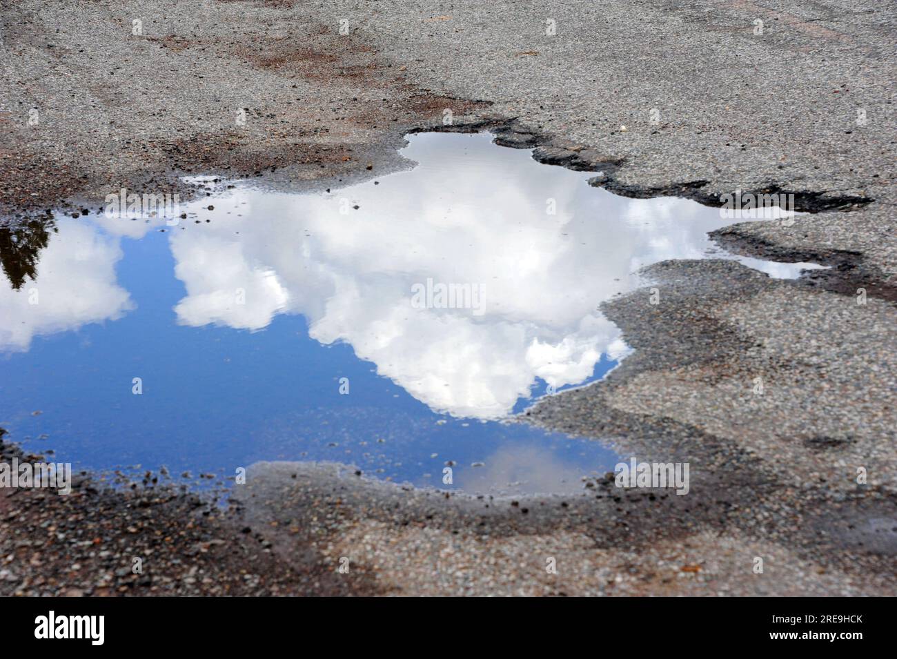 An otherwise unsightly pothole is beautified with a sky reflection in ...