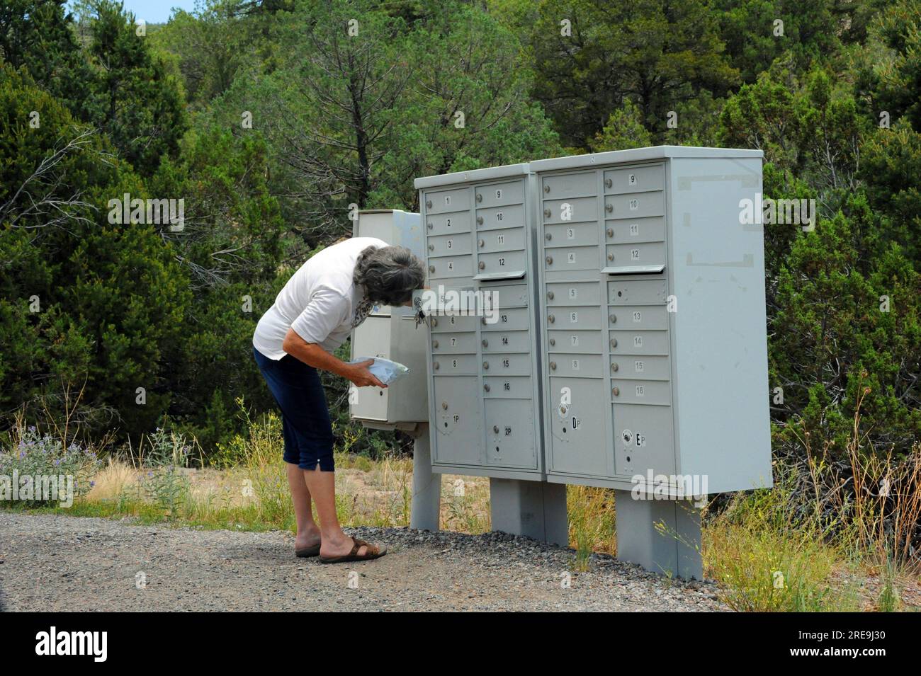 Woman bends over and unlocks her box to see if she has mail. Stacked ...