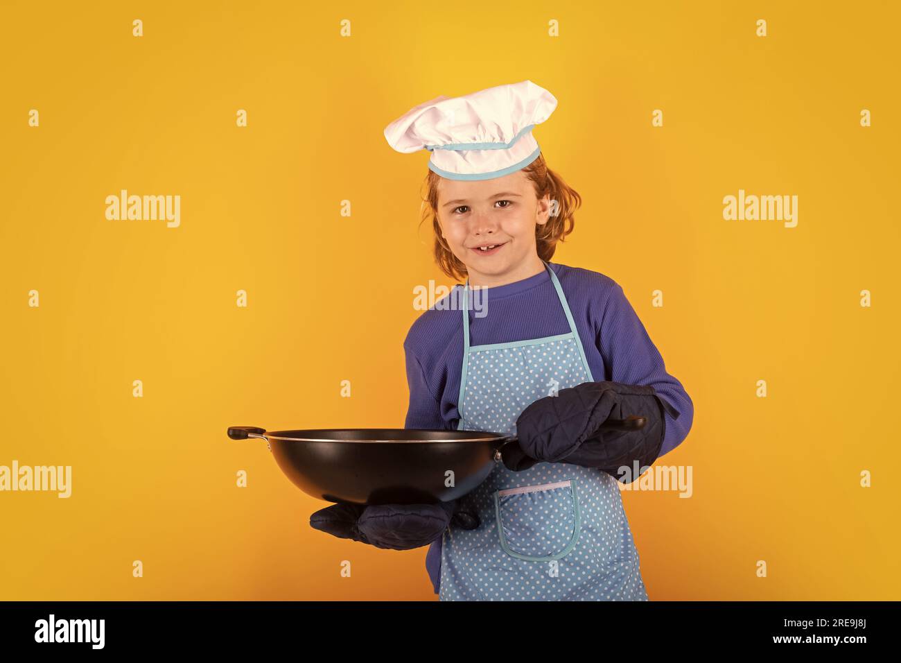 Child chef cook with cooking pan. Child chef cook prepares food on ...