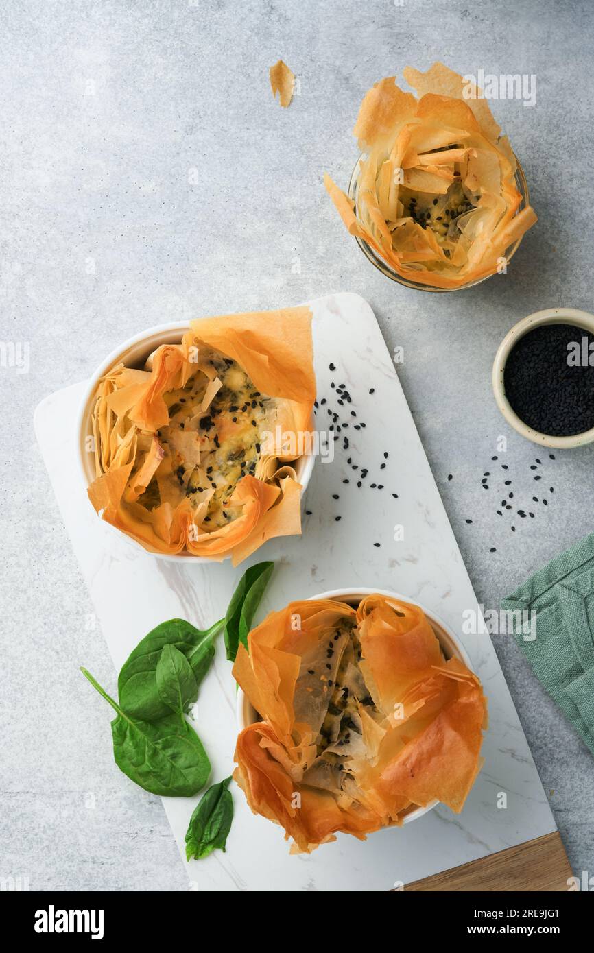 Filo pies with soft feta cheese and spinach in ceramic molds on old ...