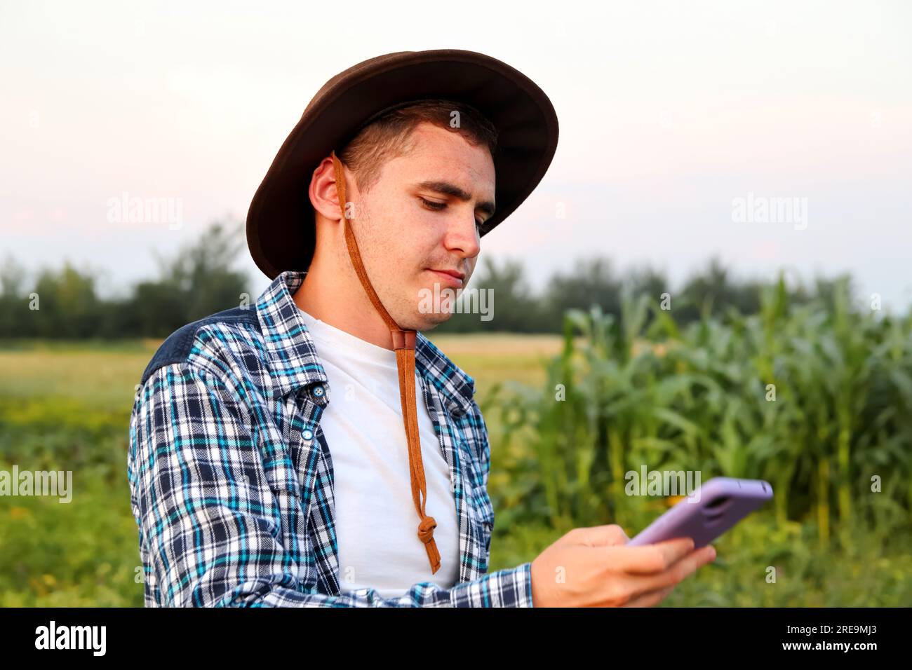 Farmer using phone. a dedicated farmer stands, attentively examining ...