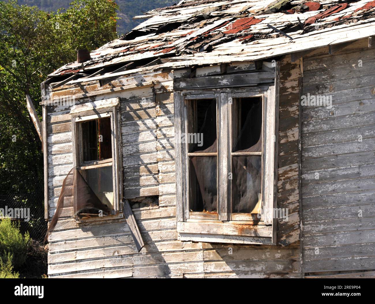 Ghost town home has empty windows with sagging screens, broken boards ...