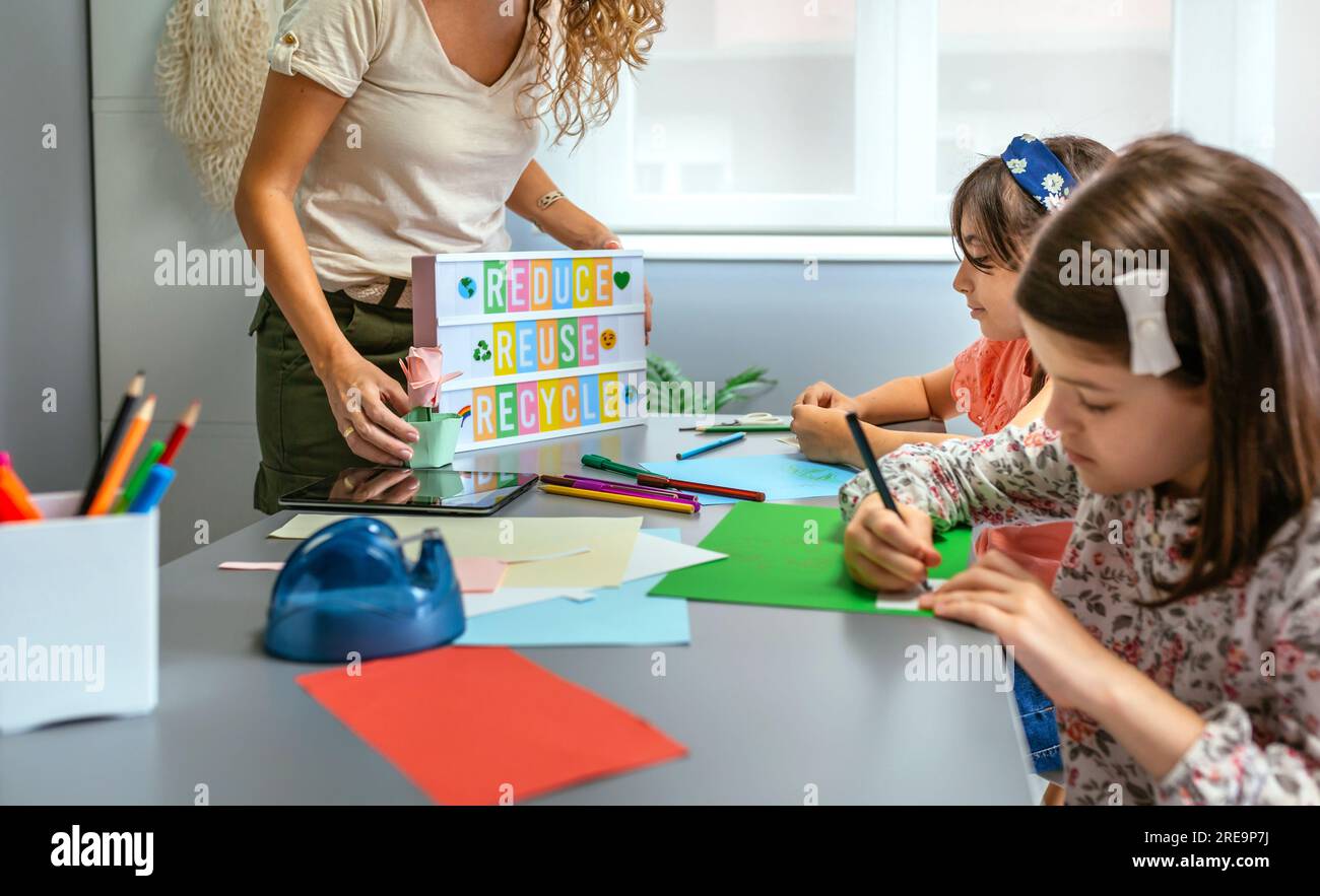 Teacher holding lightbox with text reduce, reuse, recycle while ...