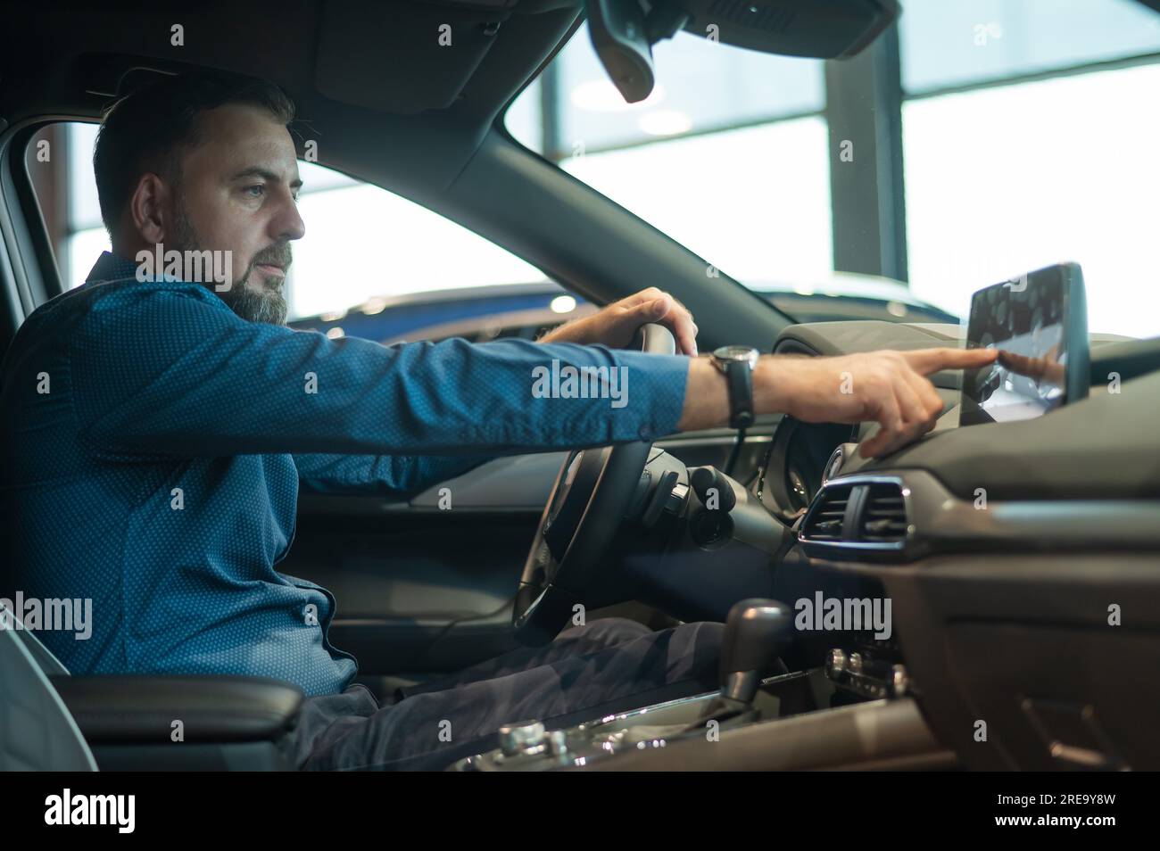 Caucasian man testing a new car in a car dealership Stock Photo - Alamy