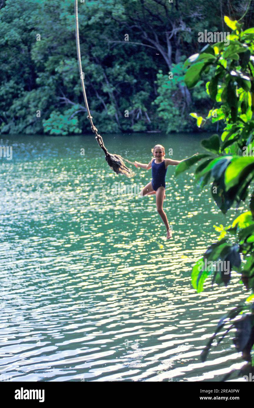 Young girl jumping off rope swing at Green lake, Big Island of Hawaii ...