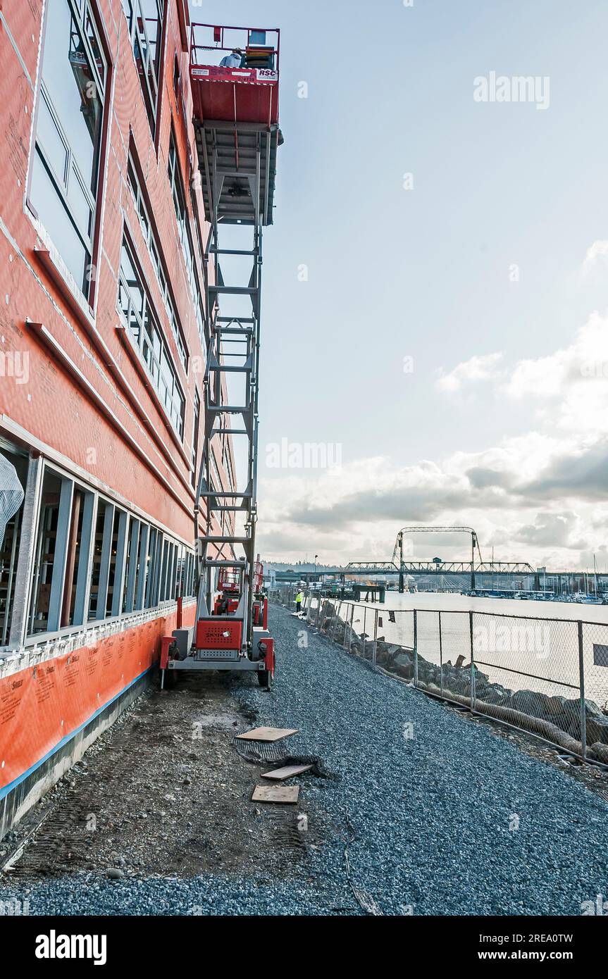 Construction of a commercial building near water. Workmen are visible ...