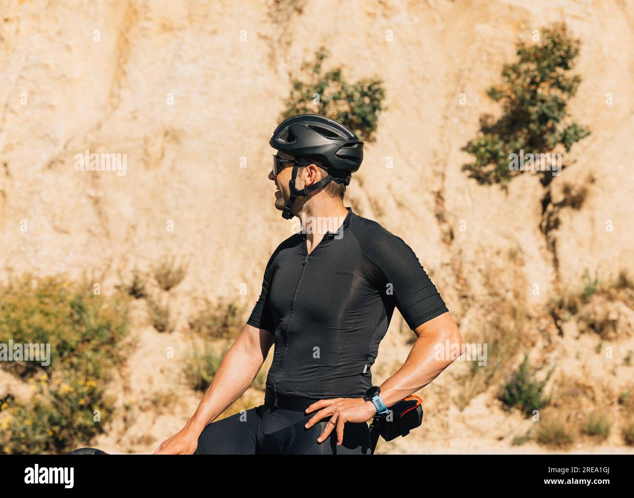 Side view of a professional cyclist in black sports attire looking away ...