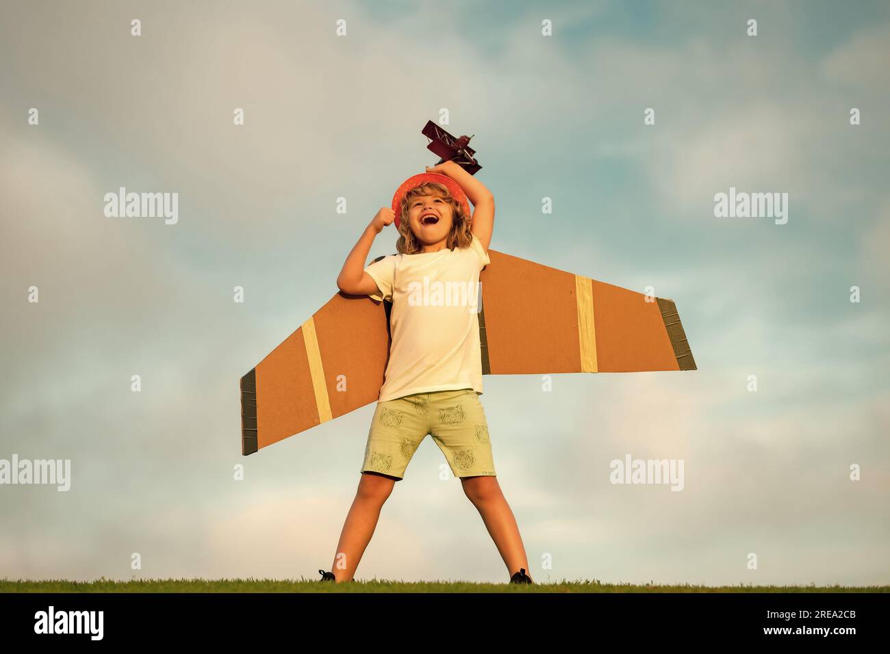 Kid pilot aviator with with paper wings dreams of traveling in summer ...