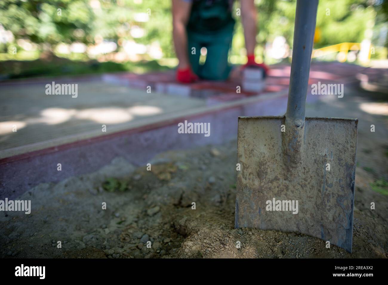 In the foreground, a shovel stuck in the ground and construction ...