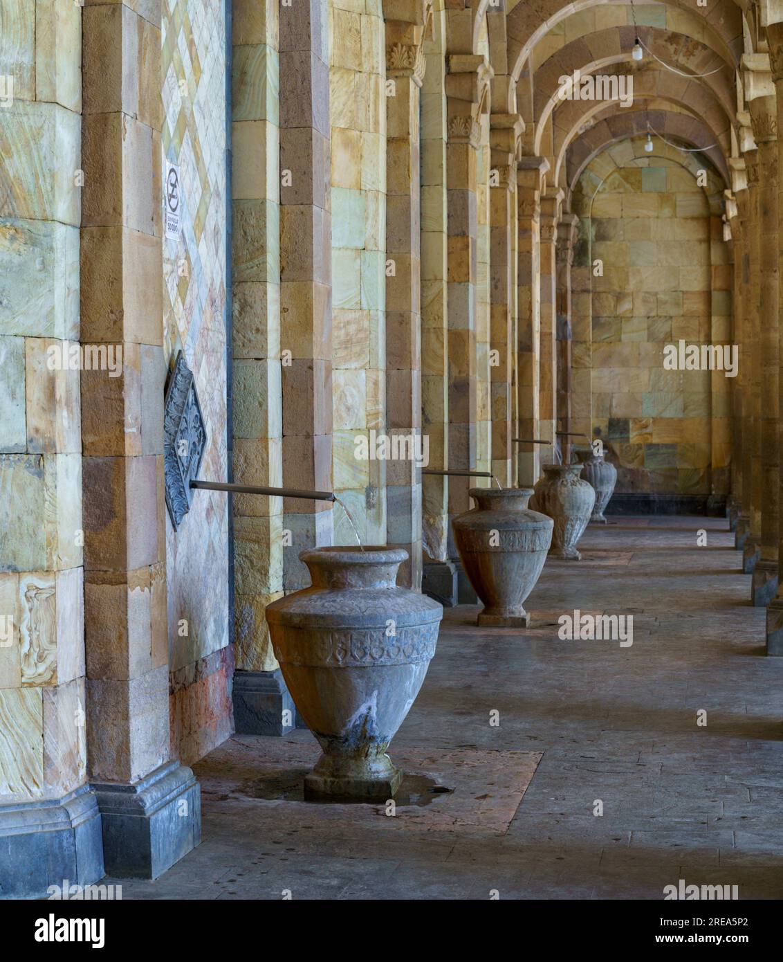 Water flows down a thin pipe into a large stone jugs in the gallery of ...