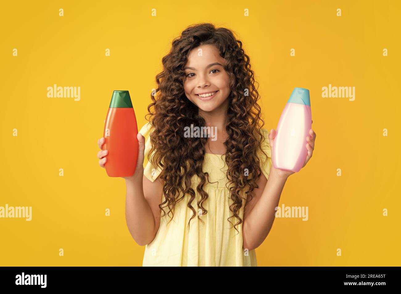 Happy teenager, portrait of child girl with bottle shampoo conditioners ...