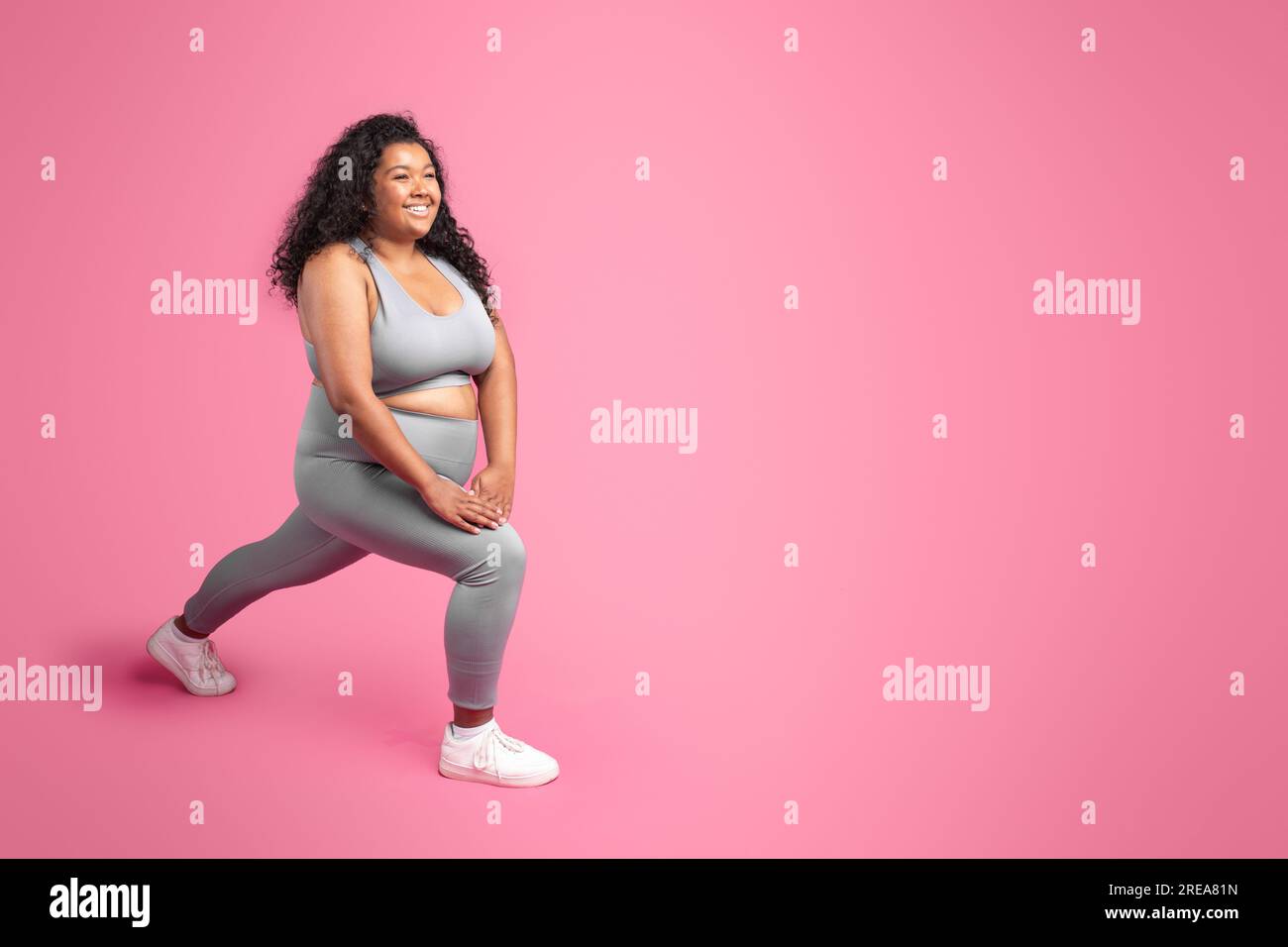 Black Plus Size Woman Training Stretching Legs And Making Lunges Pink