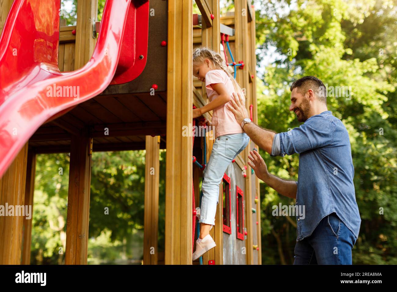 Father supporting and holding his child girl on stairs at children ...