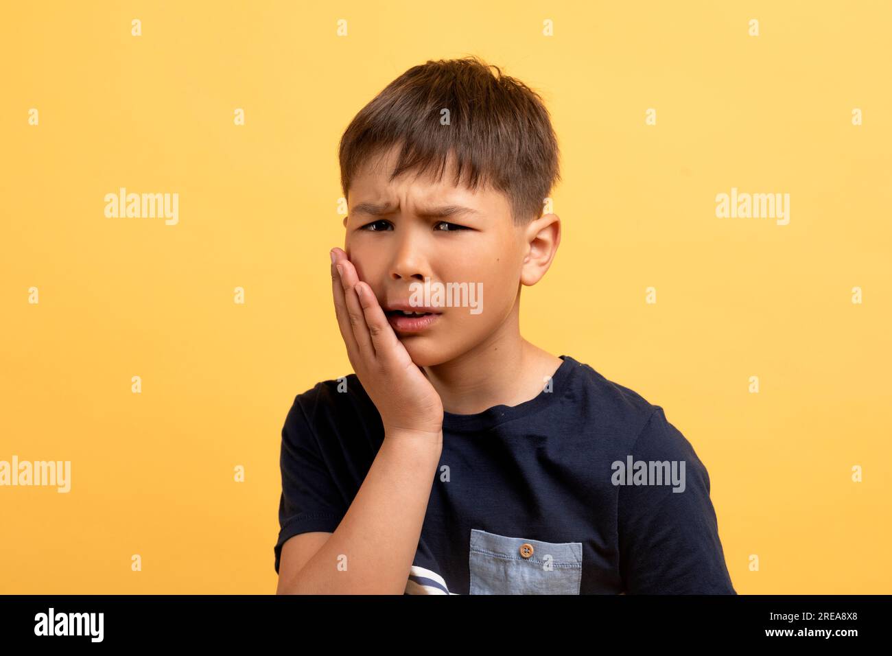 Portrait of unhealthy school aged boy touching cheek Stock Photo - Alamy