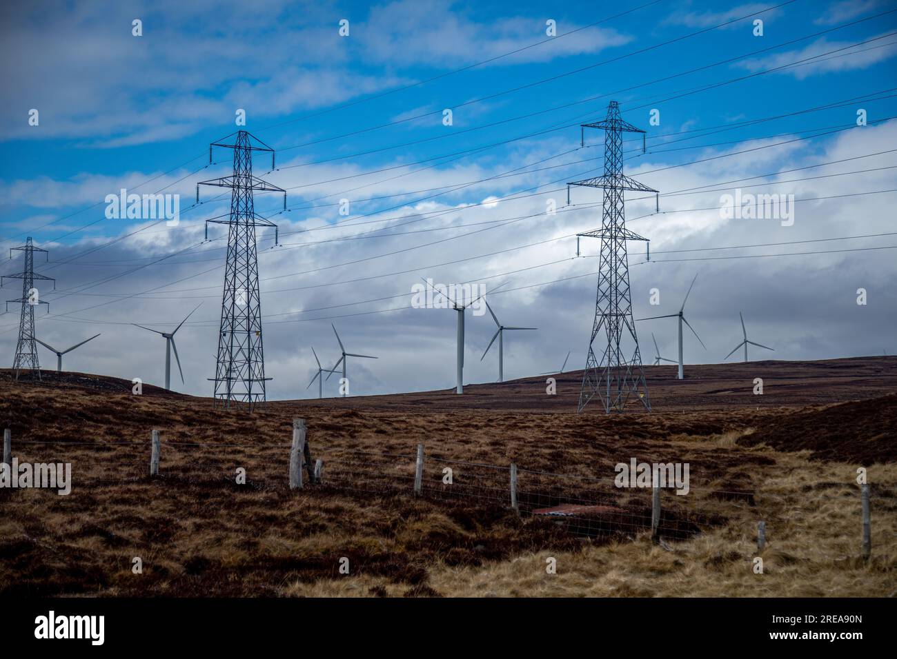 Overhead power lines and wind turbines producing electrical energy ...