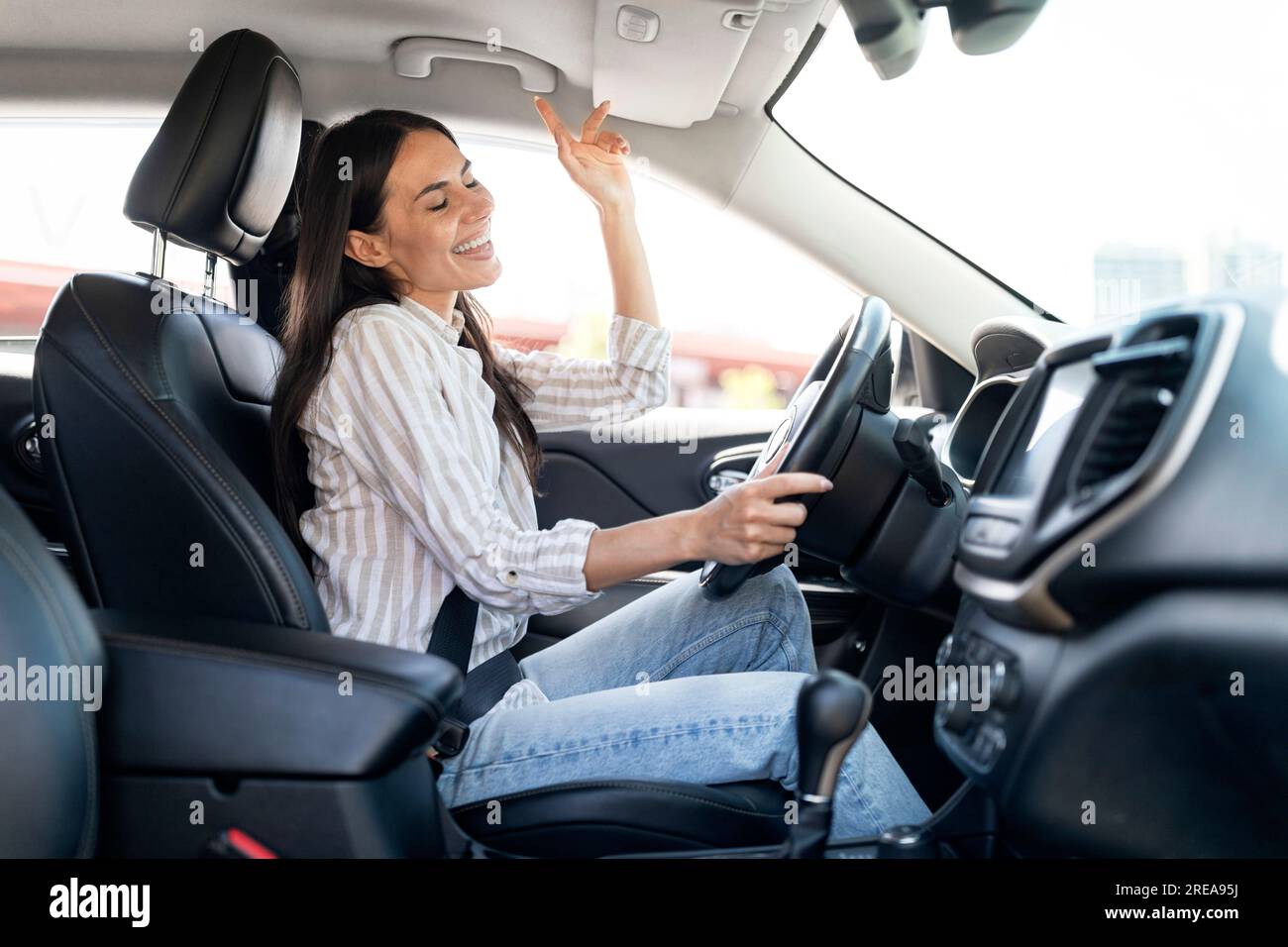 Happy pretty young woman driving car, listening to music Stock Photo ...