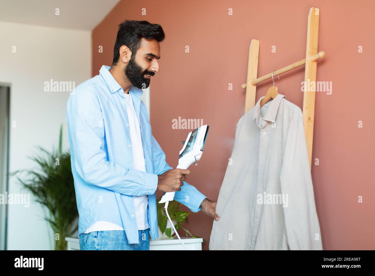 Arabian man steaming his clothing with steamer device at home Stock ...
