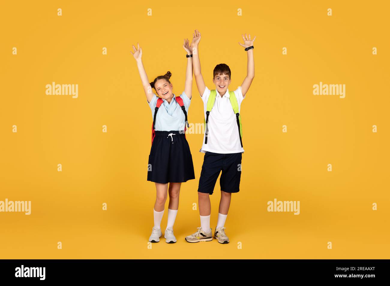 Glad caucasian teen girl and boy pupil raising hands up, celebrating ...