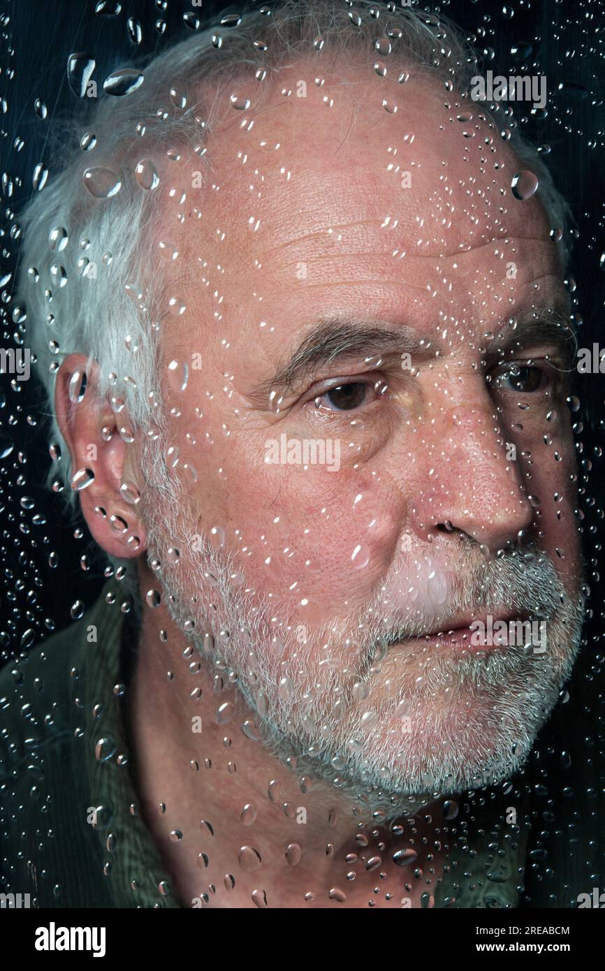 Face behind glass. Portrait of an elderly man behind a plexiglass pane ...