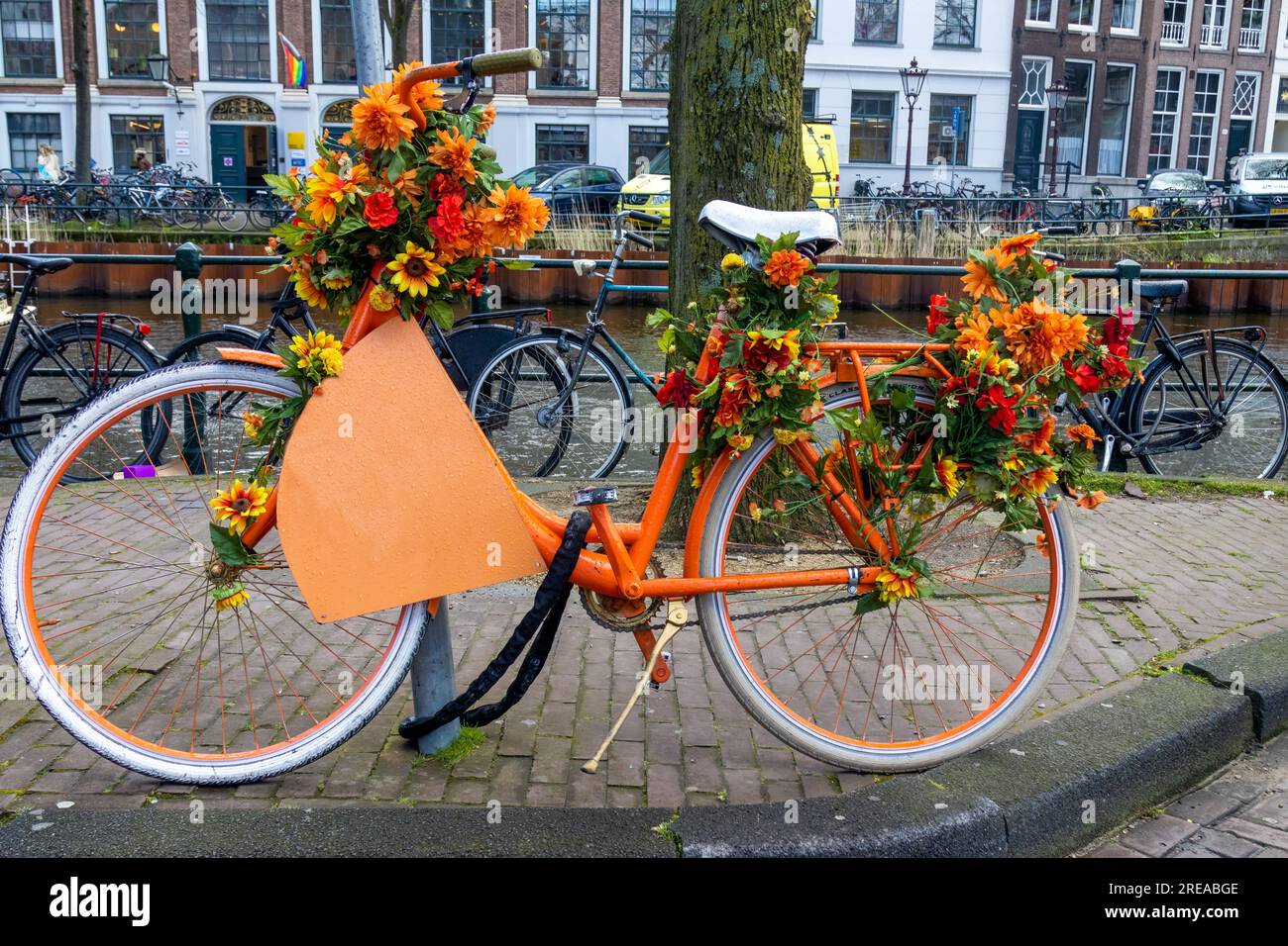 Orange bicycle decorated with lots of orange flowers by the side of a ...