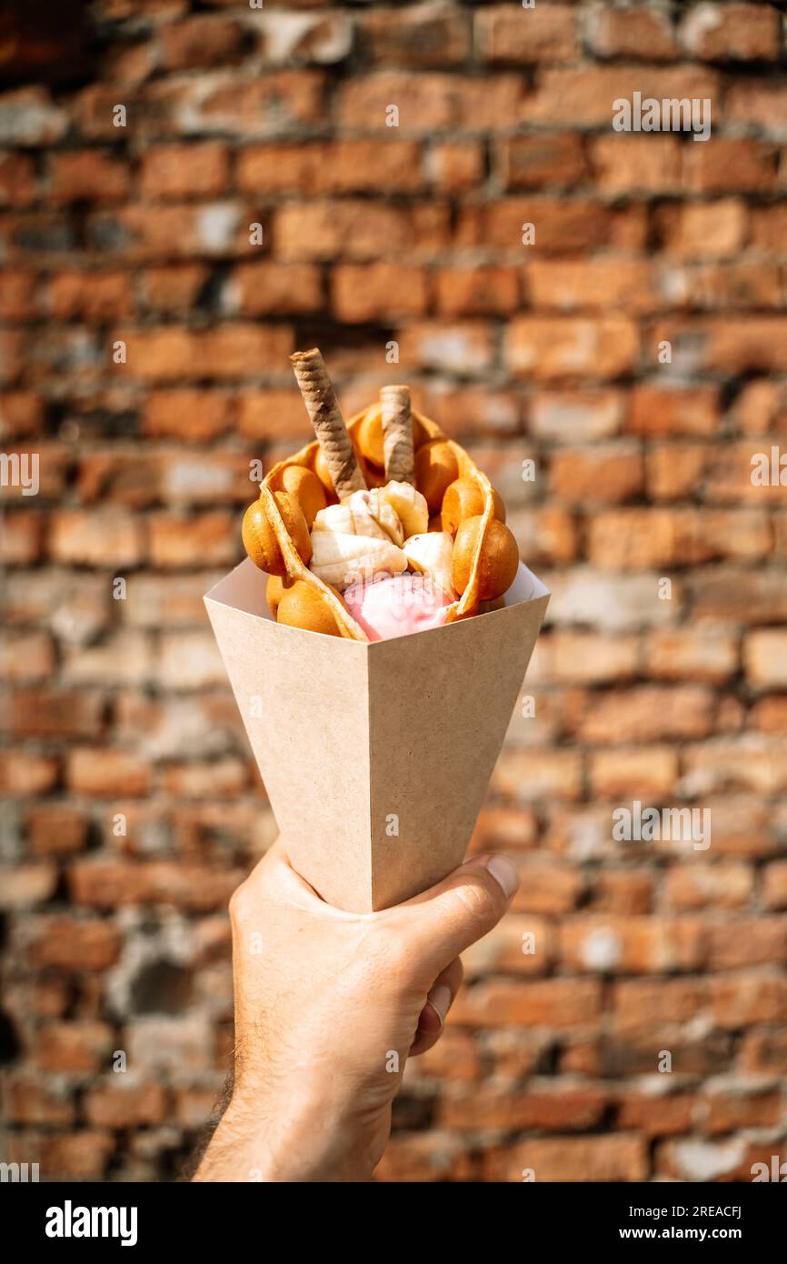 Street food dessert Belgian waffles in hand on a colored wall ...
