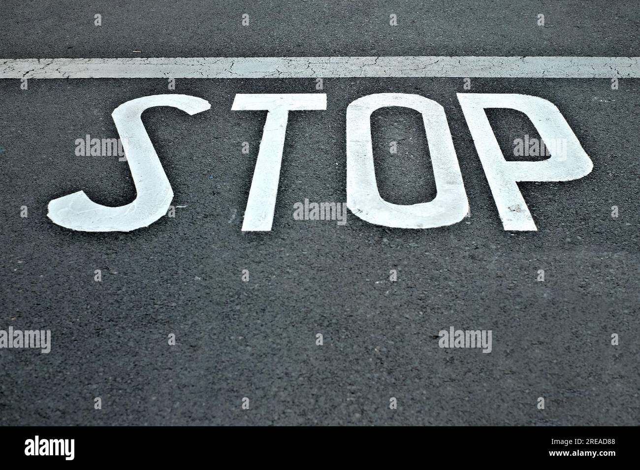Word STOP in white letters on black asphalt background Stock Photo - Alamy