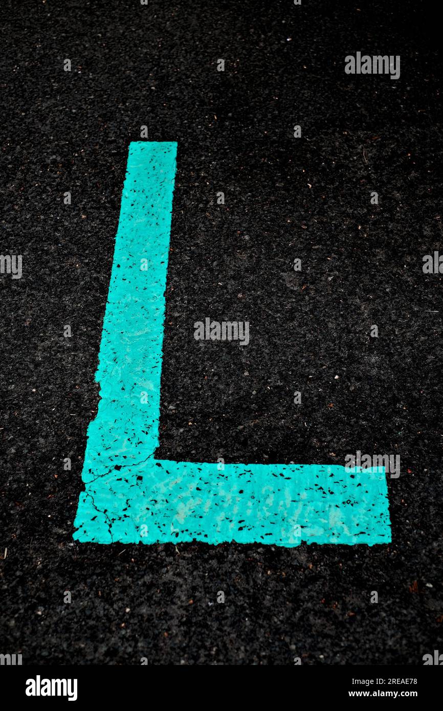 Blue letter L painted in light blue on black, road marking paint on ...