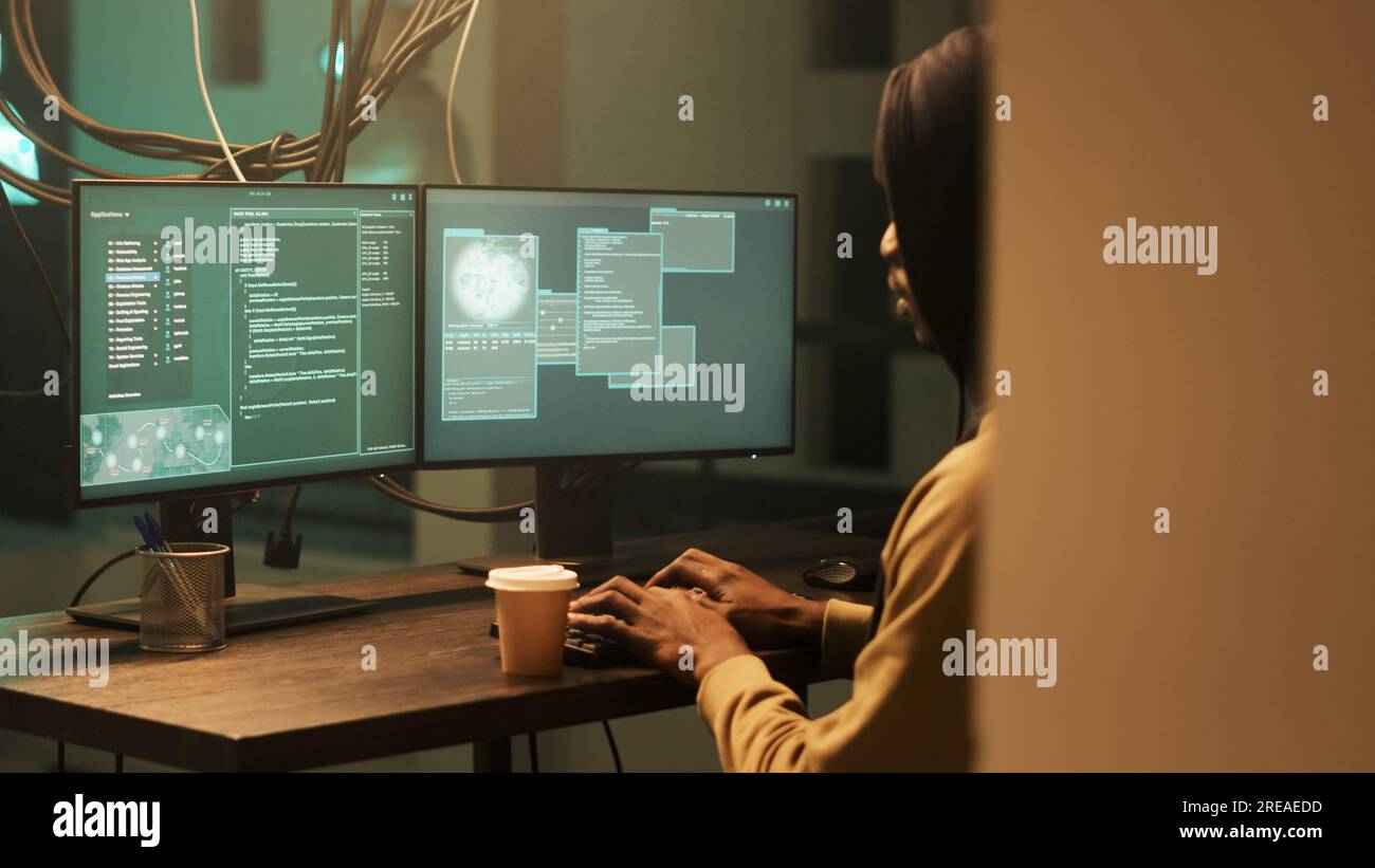 African american spy doing illegal security breach at night, working on cyberbullying to break ...