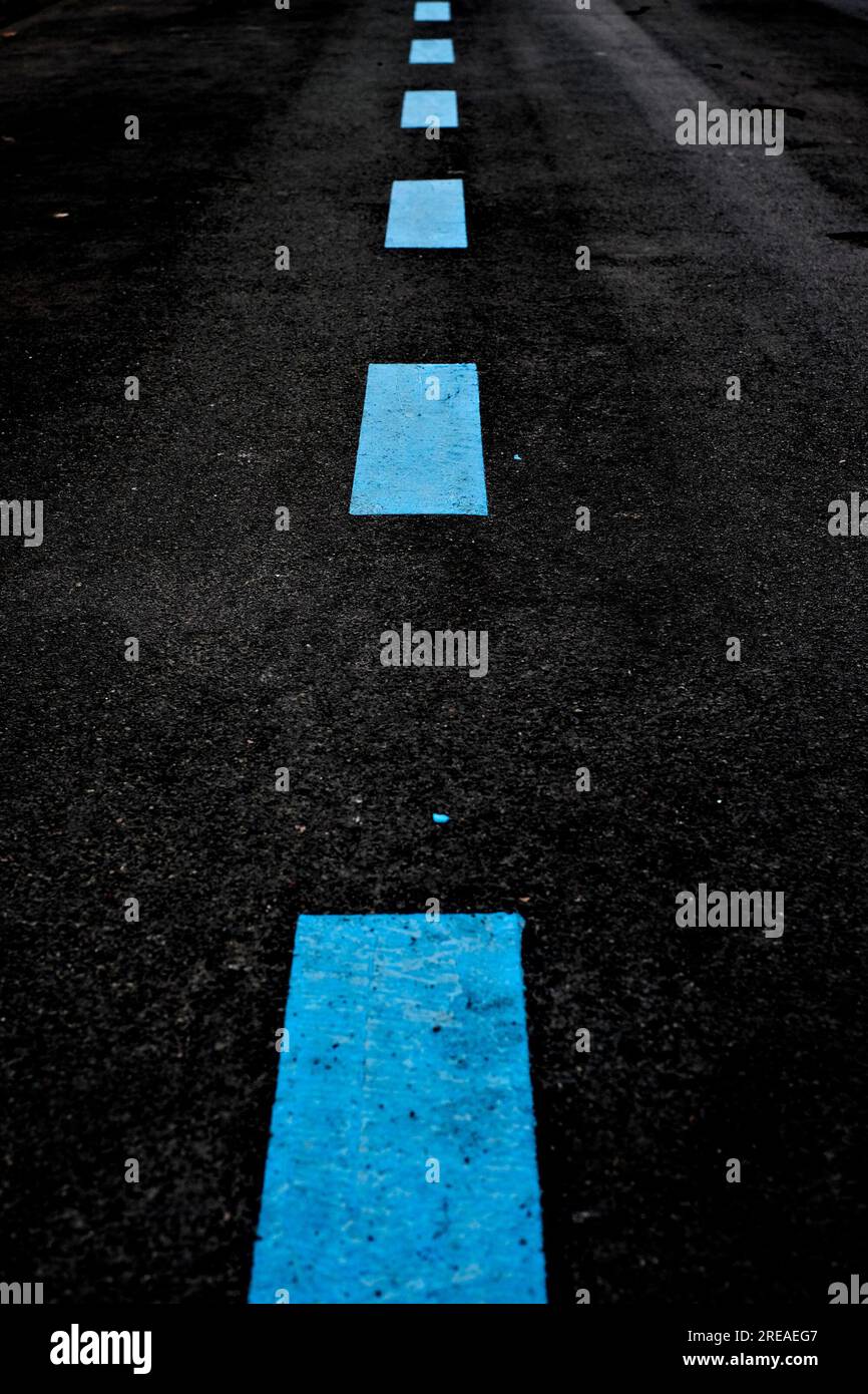 Dashed blue road marking line in perspective, centered in the frame ...