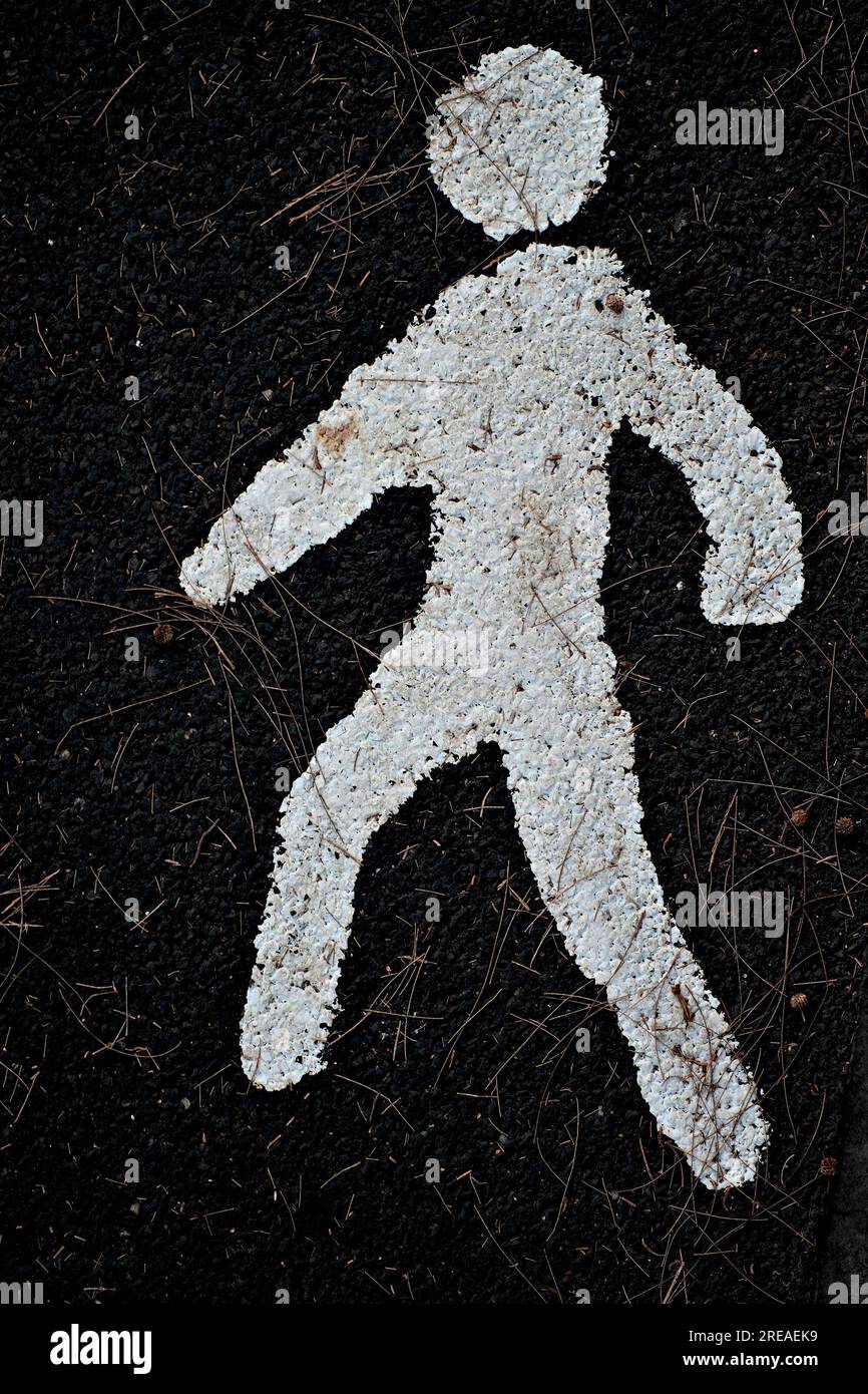 White human figure painted on black background, road signage on tarmac ...