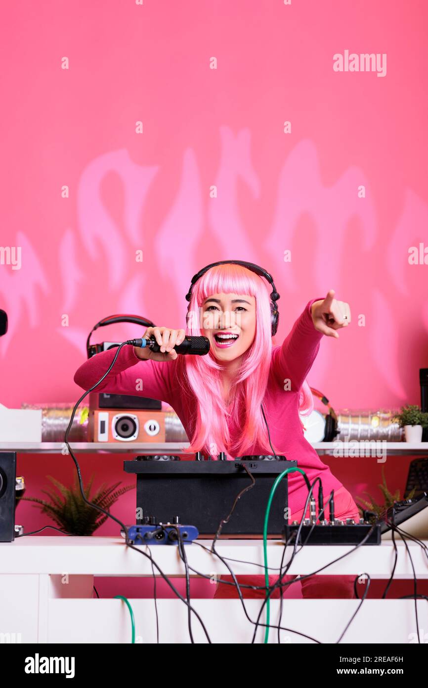 Woman performer sitting at dj table performing techno music using ...