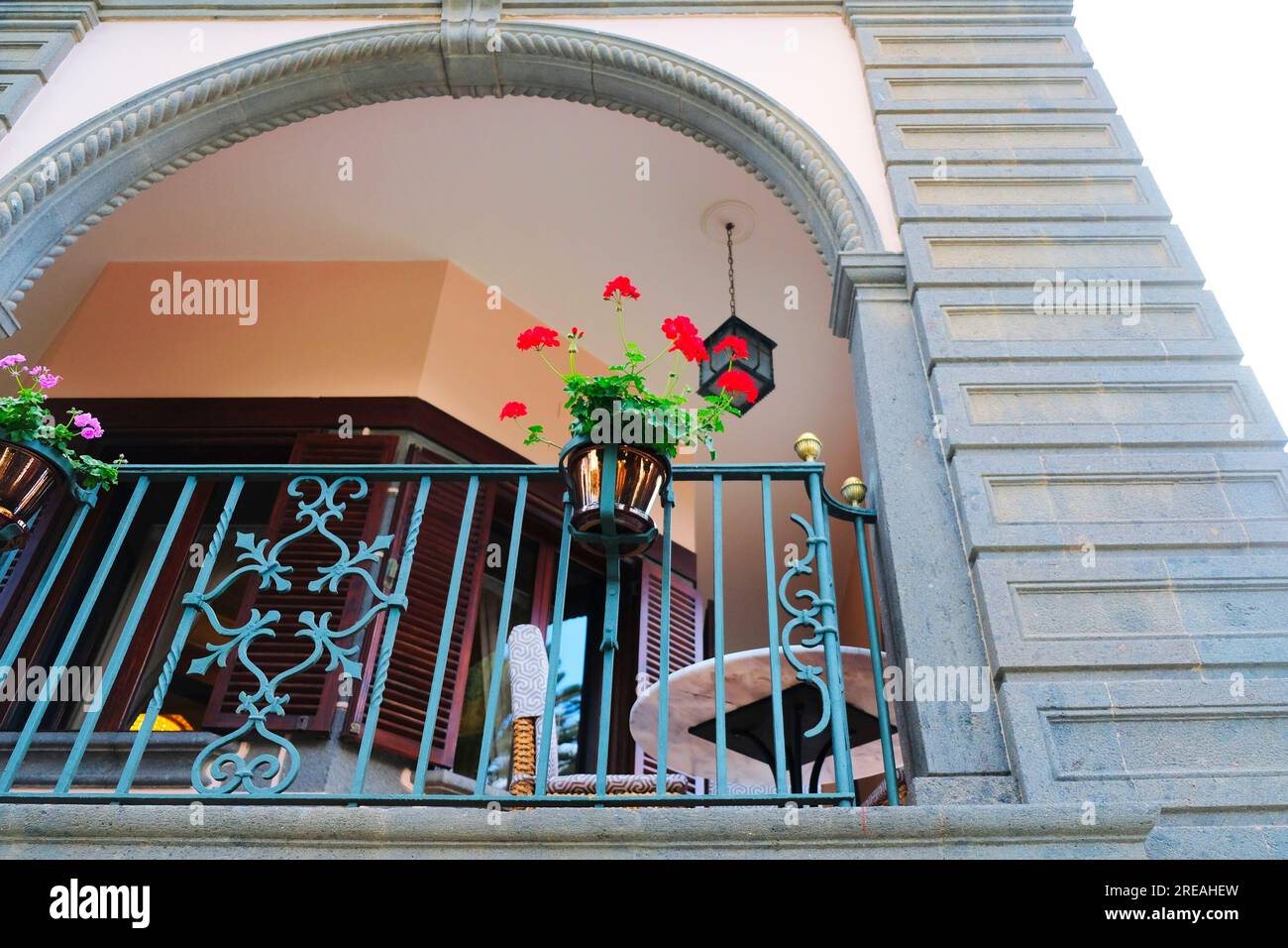 Red geranium plant in a pot on an elegant classic balcony of a classic ...