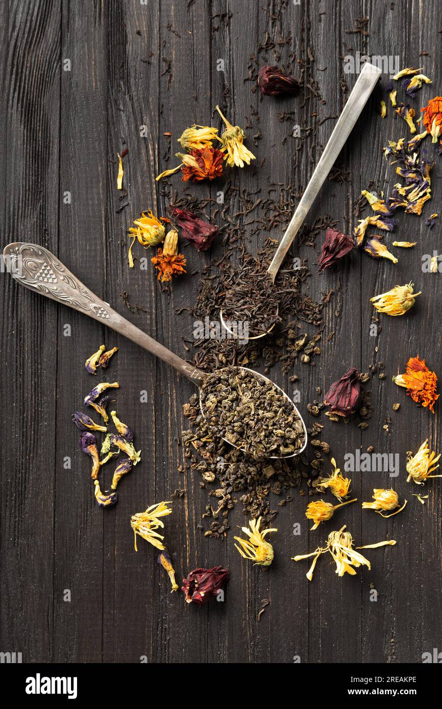Composition of dry black and green tea in vintage spoons, dry flowers ...
