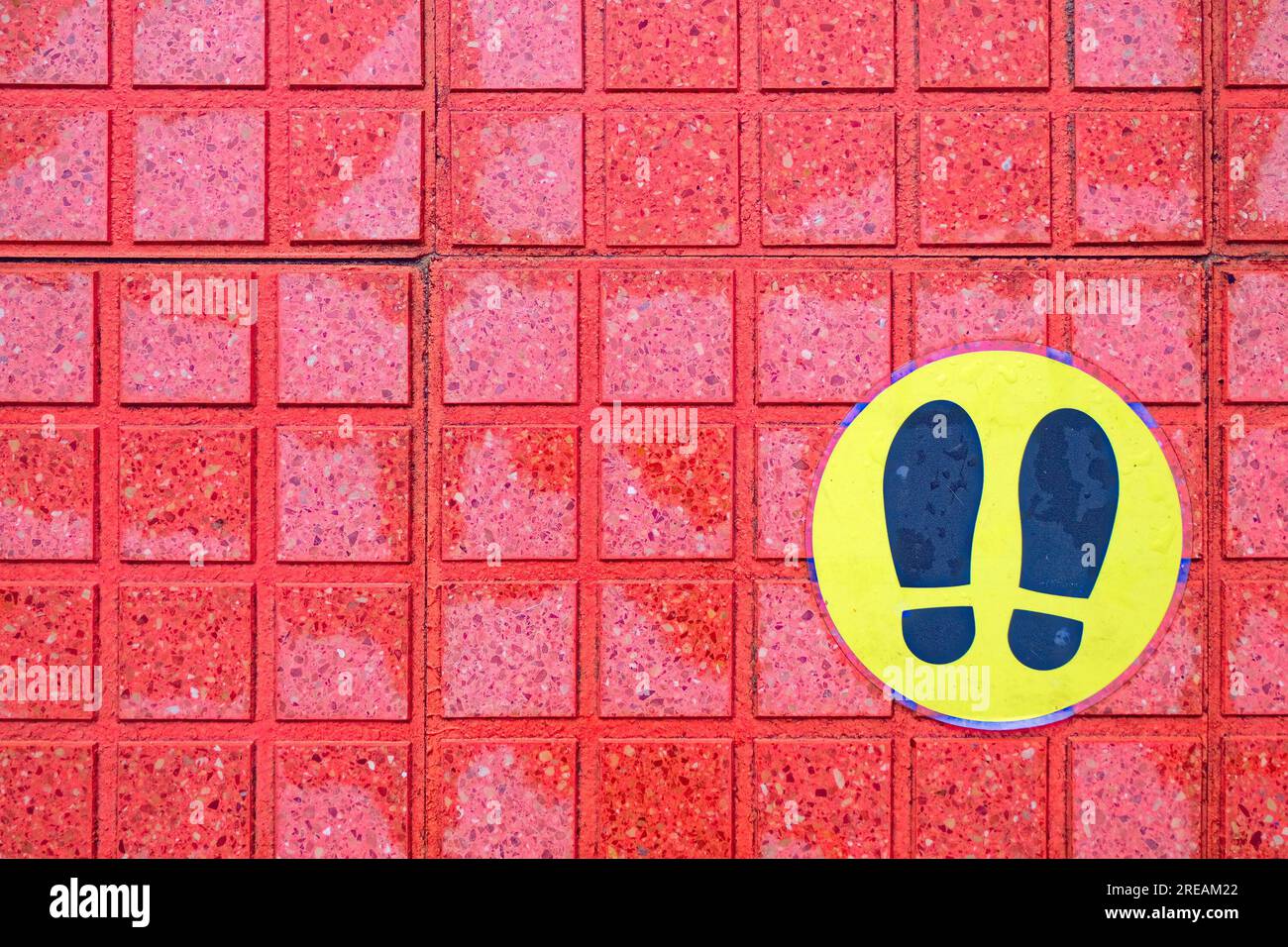 Wet red floor and a sign with two black footprints in a yellow circle ...