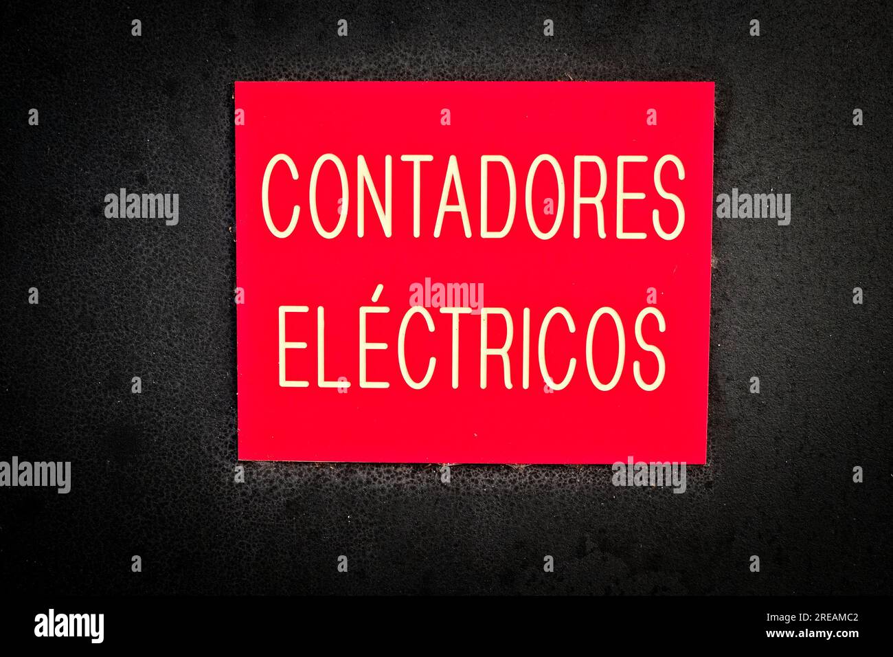 Red warning plate on black background, with text in Spanish (contadores ...